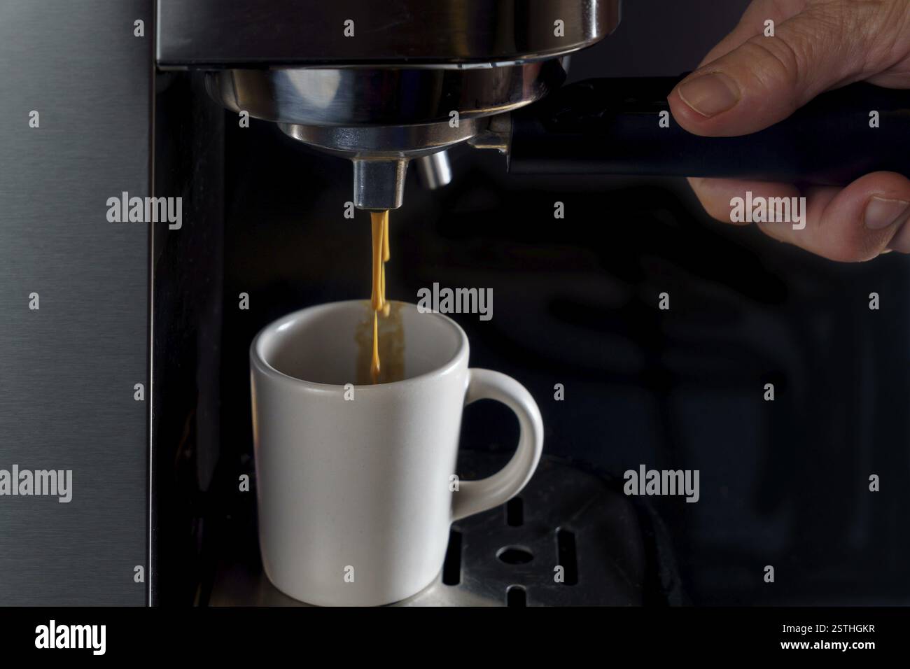 Close-up of a woman's hands preparing espresso coffee in an espresso machine with a black ...