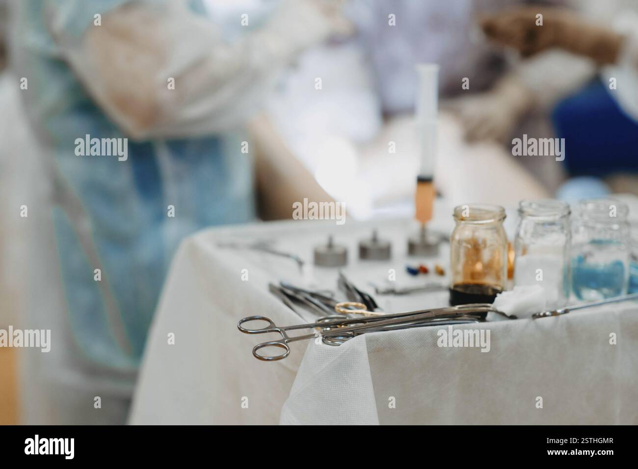 A variety of surgical tools and syringes are laid out on a medical ...