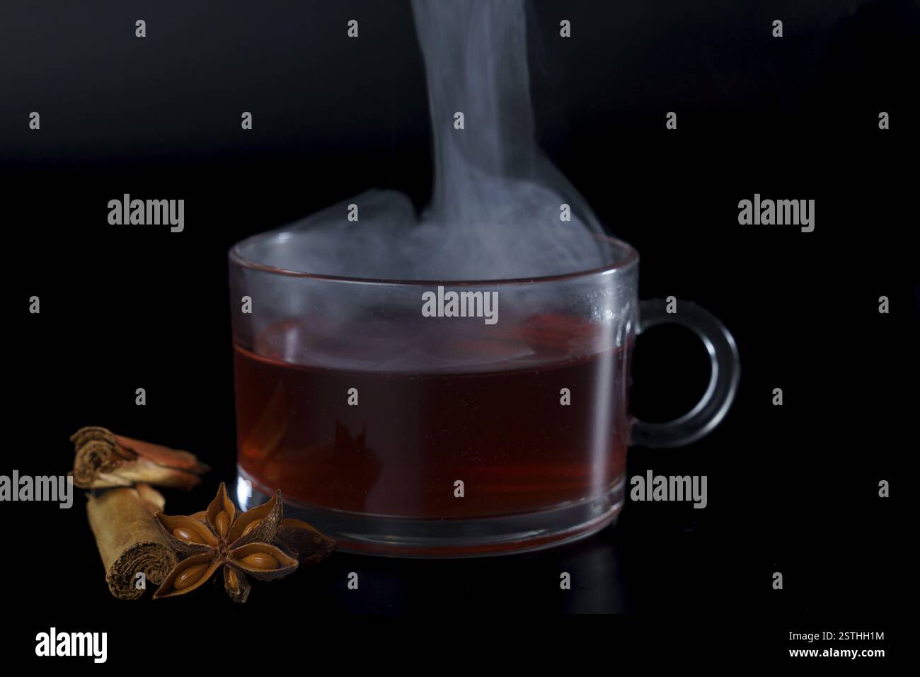 Steaming hot cup of red tea with star anise and cinnamon stick, with ...