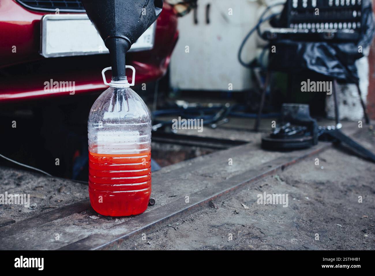 A garage scene with red liquid being poured into a bottle using a ...