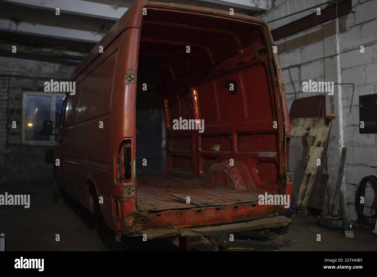 An old, red van with an open rear inside a dimly lit warehouse Stock ...
