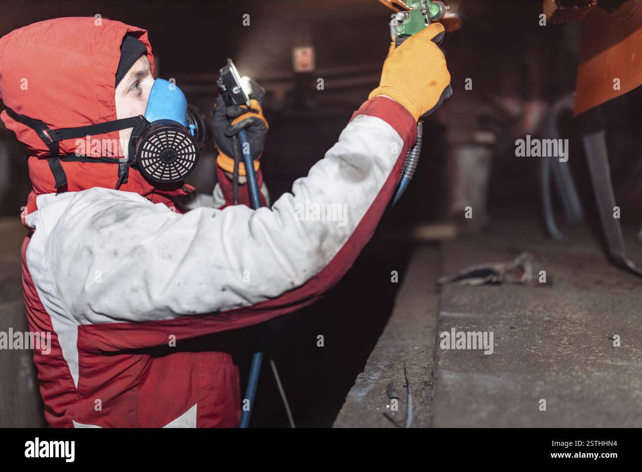 Person in a safety suit using a spray gun on a car's underside Stock ...