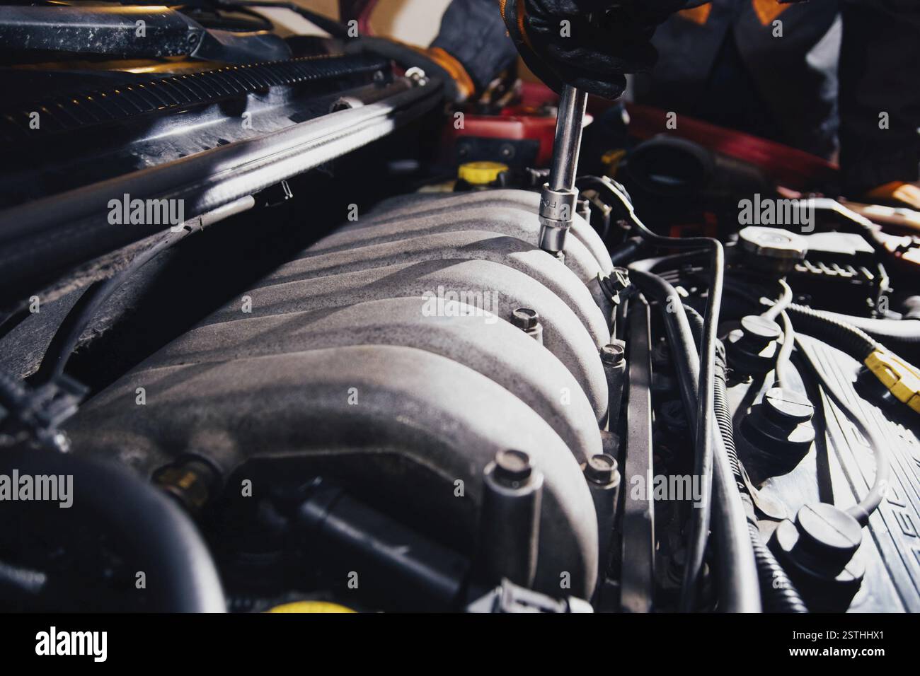 Mechanic using a wrench on a car engine, wearing black gloves ...