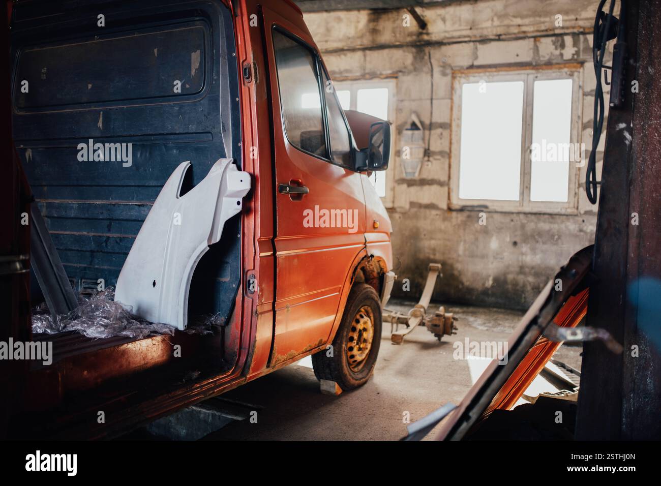 Old red van inside a garage with visible repairs and parts scattered ...