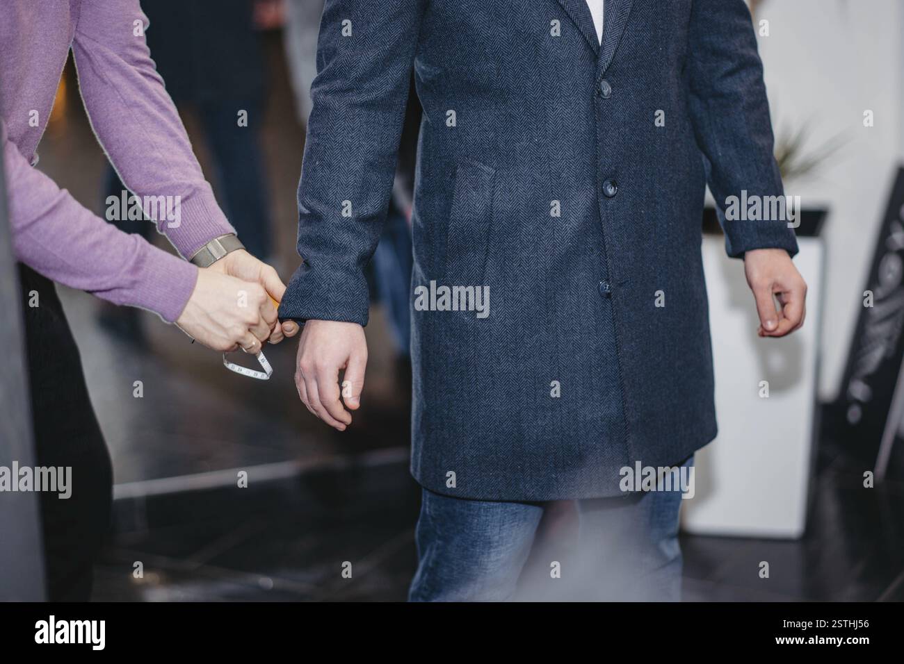 A person in a dark coat handcuffed by someone in a purple sweater ...