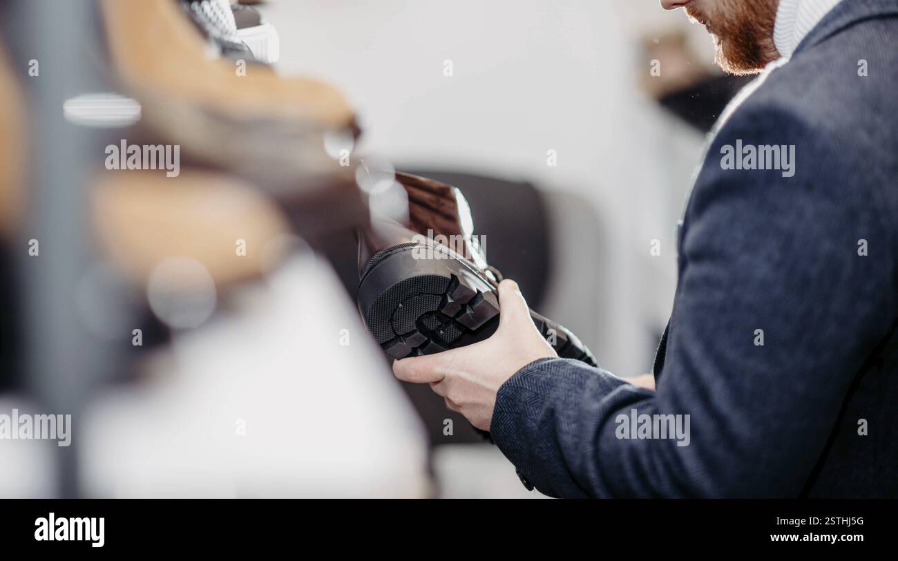 A person inspecting a shoe in a store with shoes displayed on a shelf ...