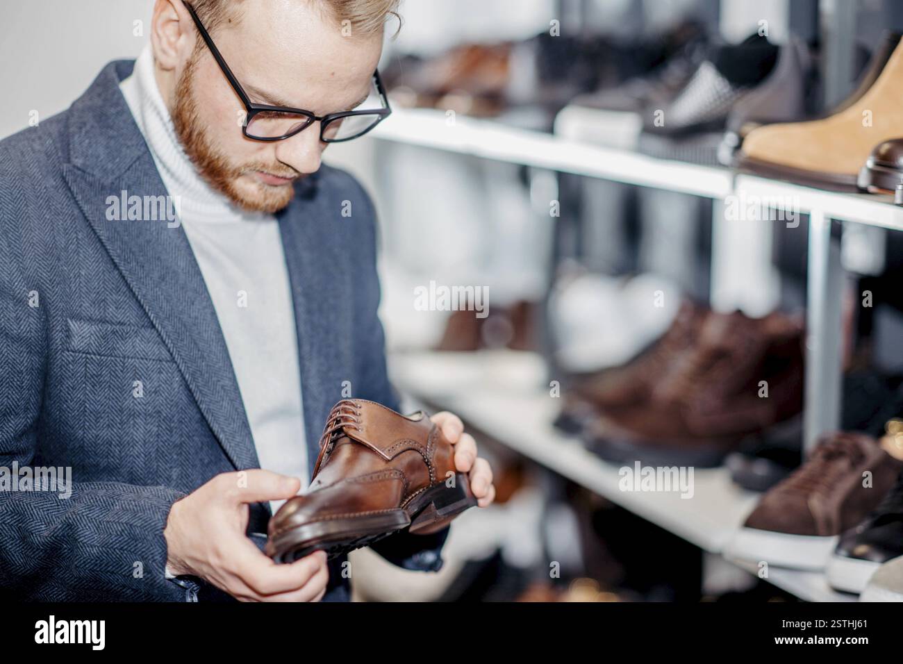 Man closely examining a brown leather shoe in a store Stock Photo - Alamy