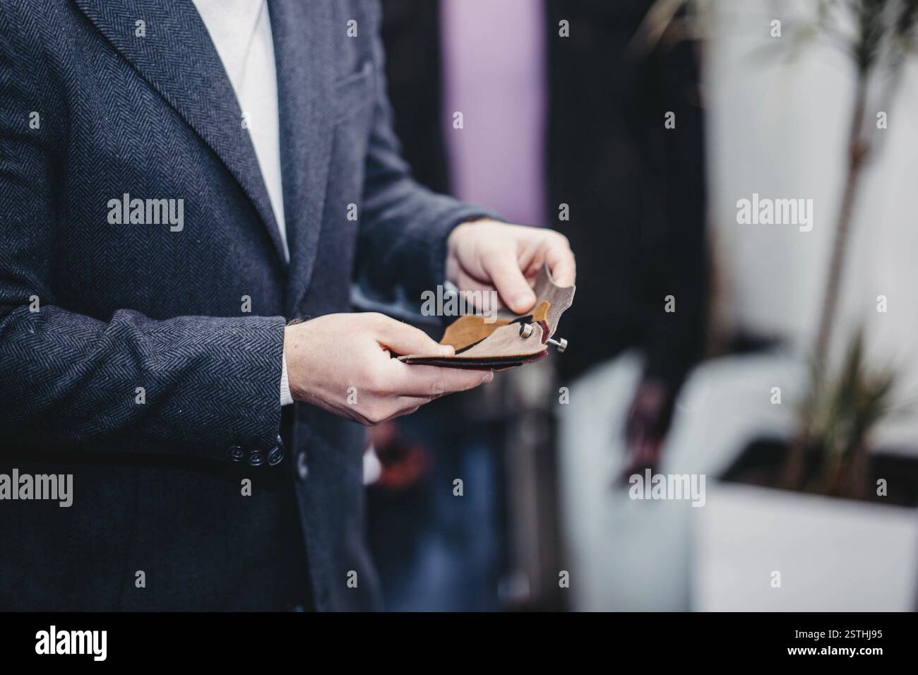 Close-up of hands in formal attire examining a fabric sample, focused ...