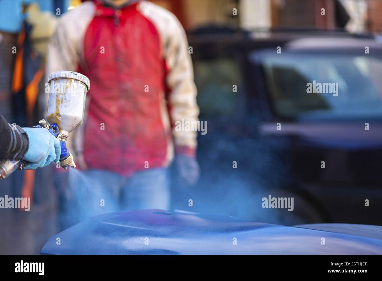 Person spray painting a car in a workshop with blue paint Stock Photo ...