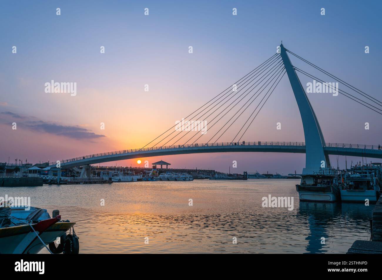A picturesque sunset at the Tamsui River estuary, featuring the iconic Lover's Bridge and ...