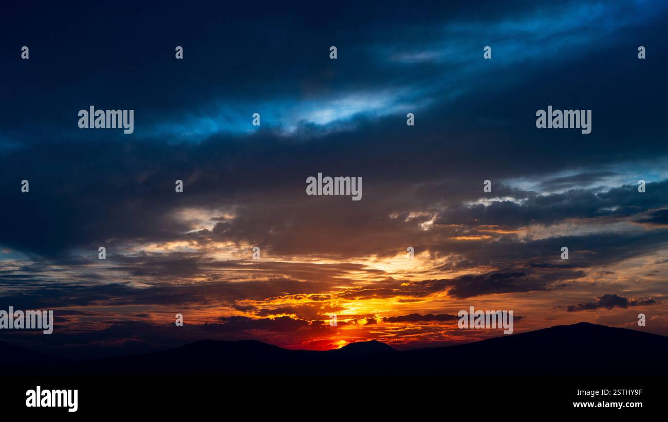 Cloudy sunset with sun gone behind the mountains in the lake of ...