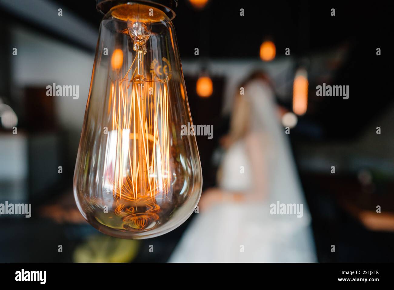 stylish groom and happy bride kissing under retro bulbs lights in ...