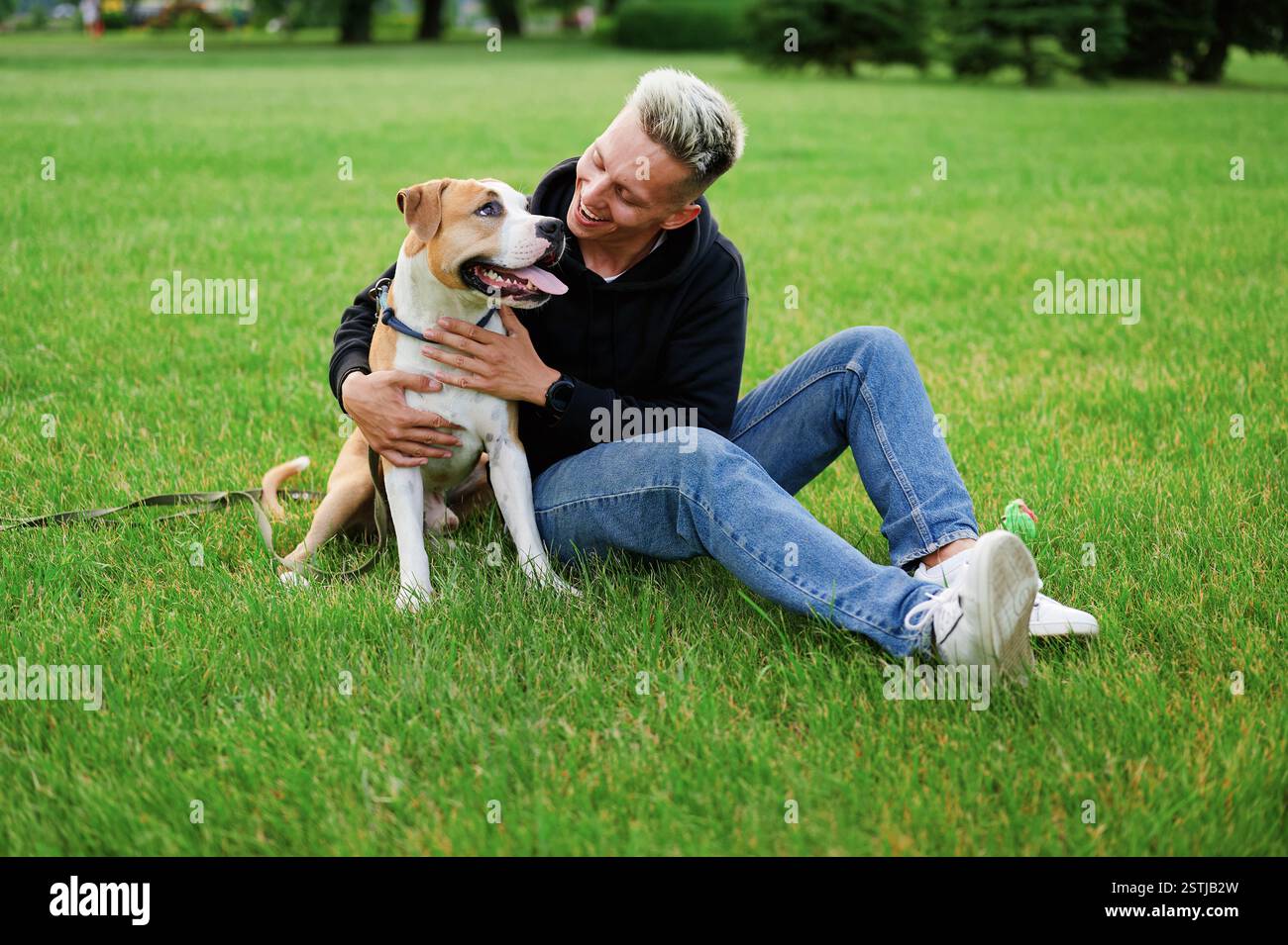 Young happy man with his dog in a park - Smiling guy and puppy having ...