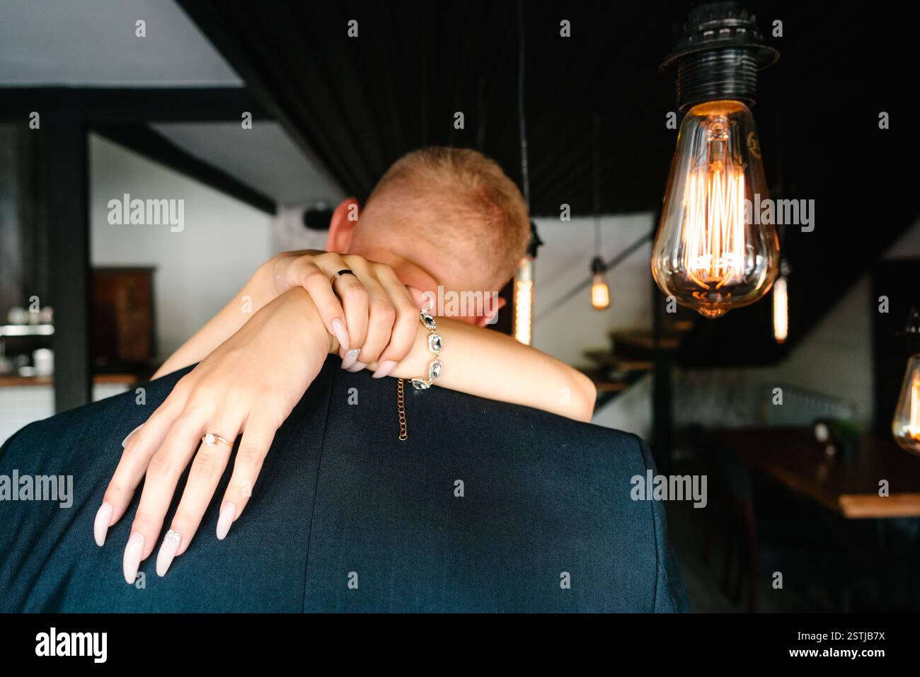 stylish groom and happy bride kissing under retro bulbs lights in ...