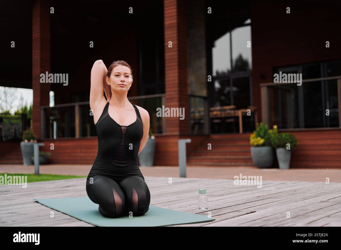 Young woman in the background of a country house sitting on a mat ...