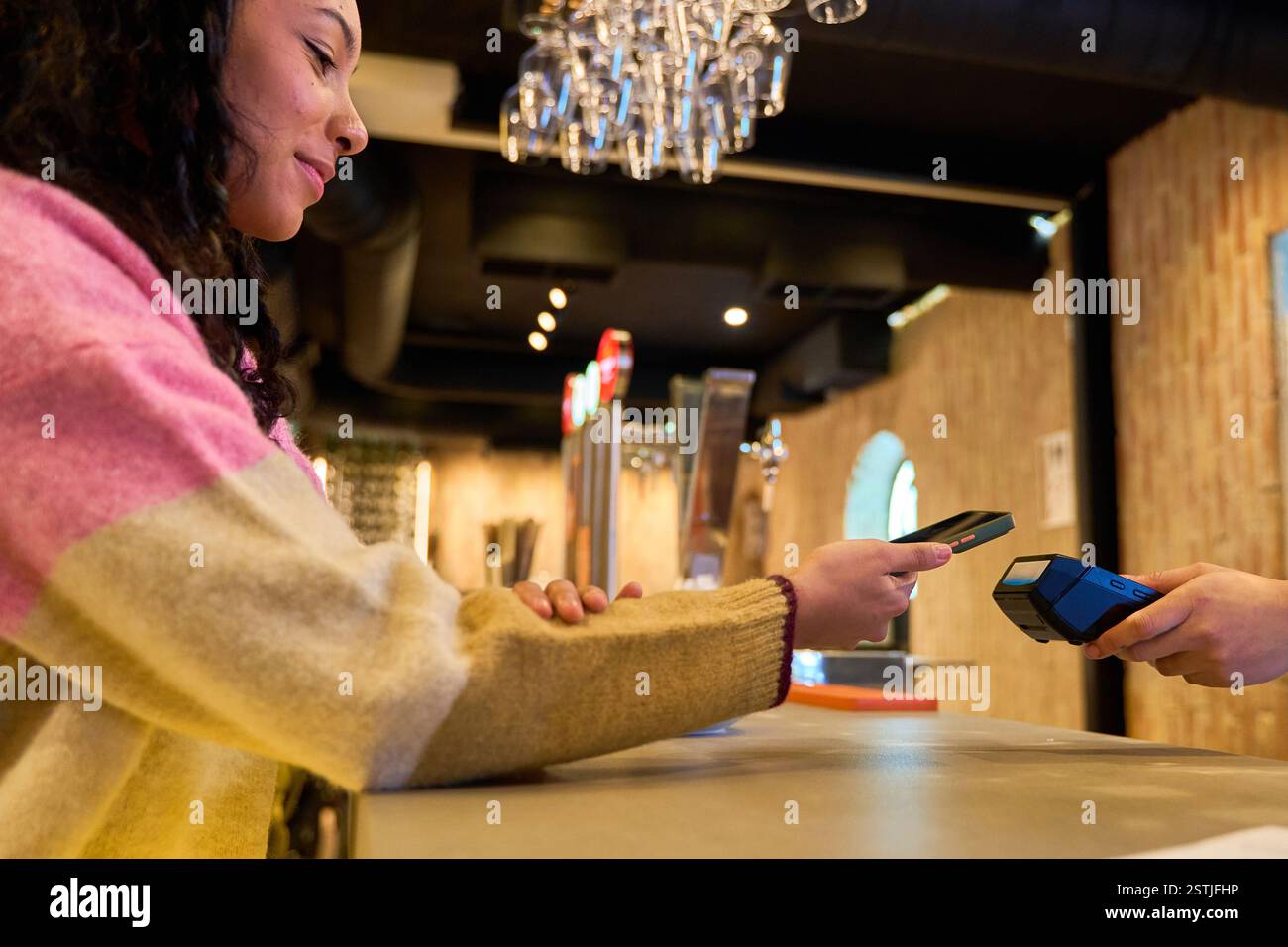 Woman paying with smartphone at bar counter using nfc technology ...