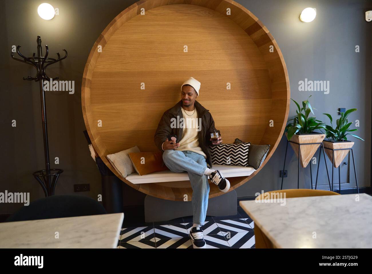 Stylish man sits comfortably in a unique circular wooden booth at a ...