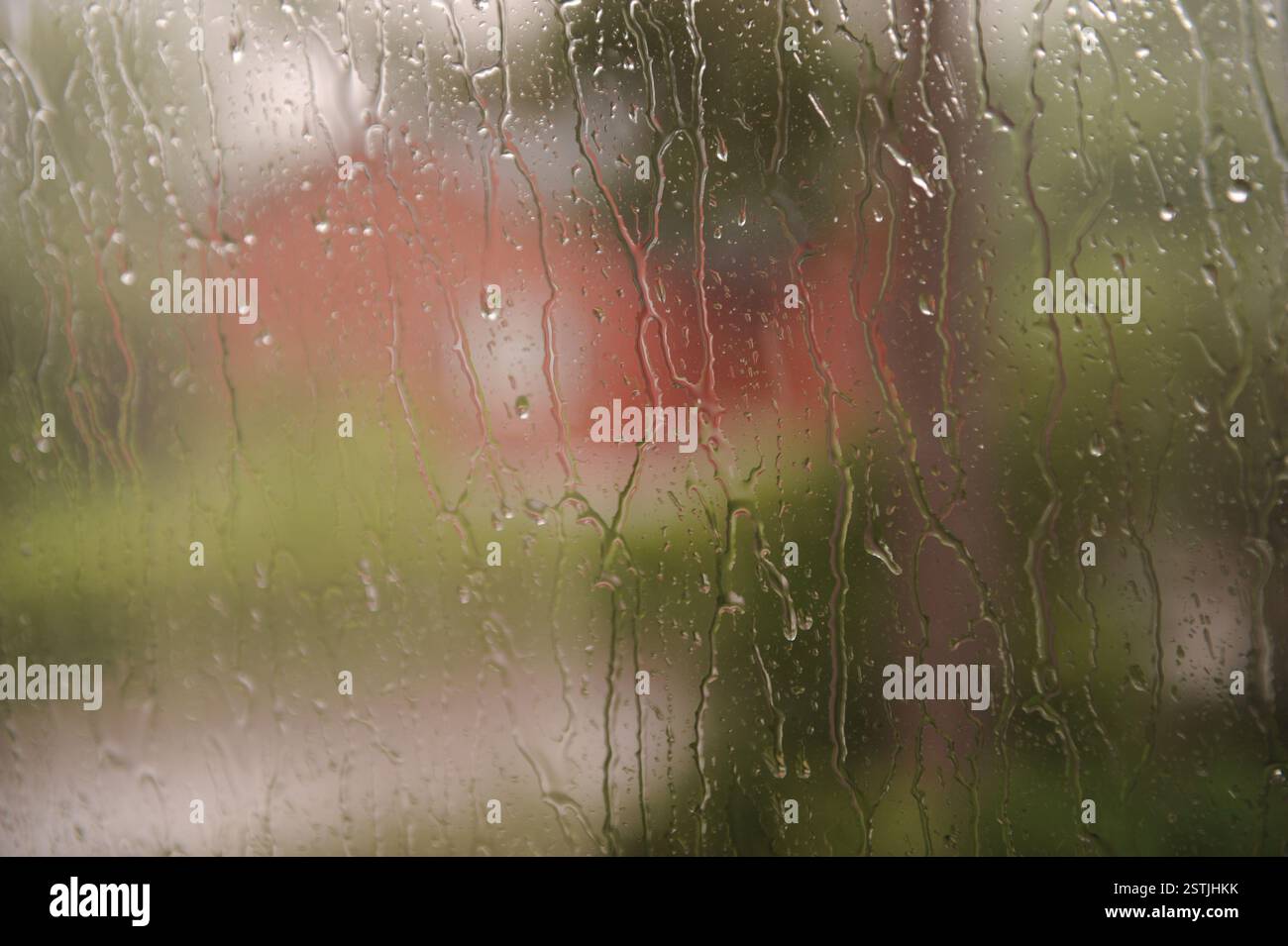 Rain running down window glass. Green and red blurry background Stock ...