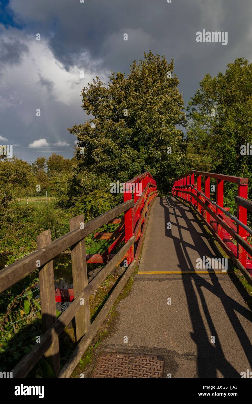 Red bridge over the River Lagan with the sun casting shadows through ...