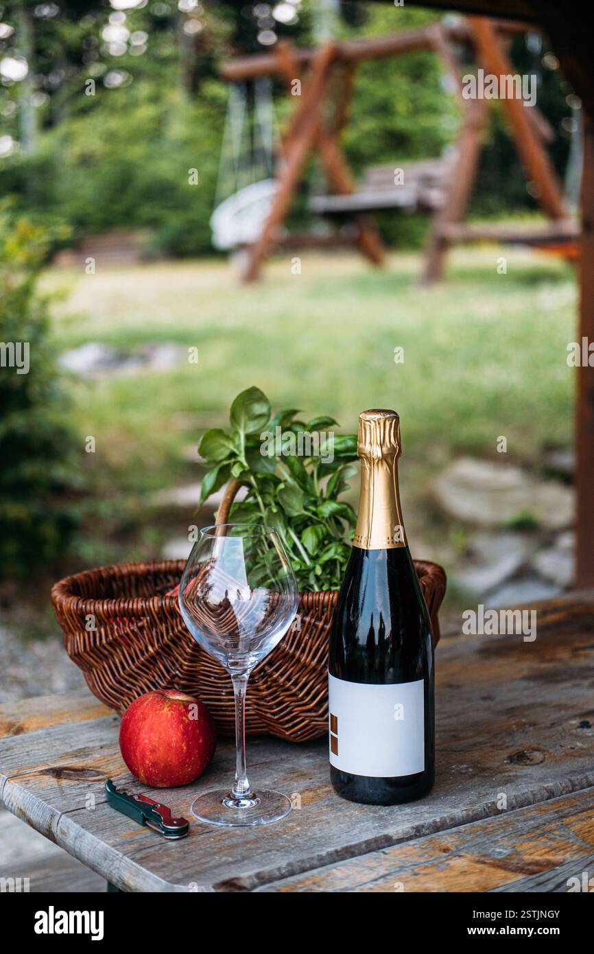 Rustic outdoor scene with wine bottle, glass, apple, and wicker basket ...
