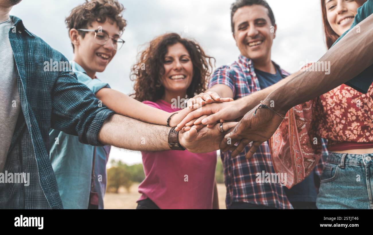 Multigenerational diverse group stacking hands in unity, showing teamwork, leadership, inclusion ...