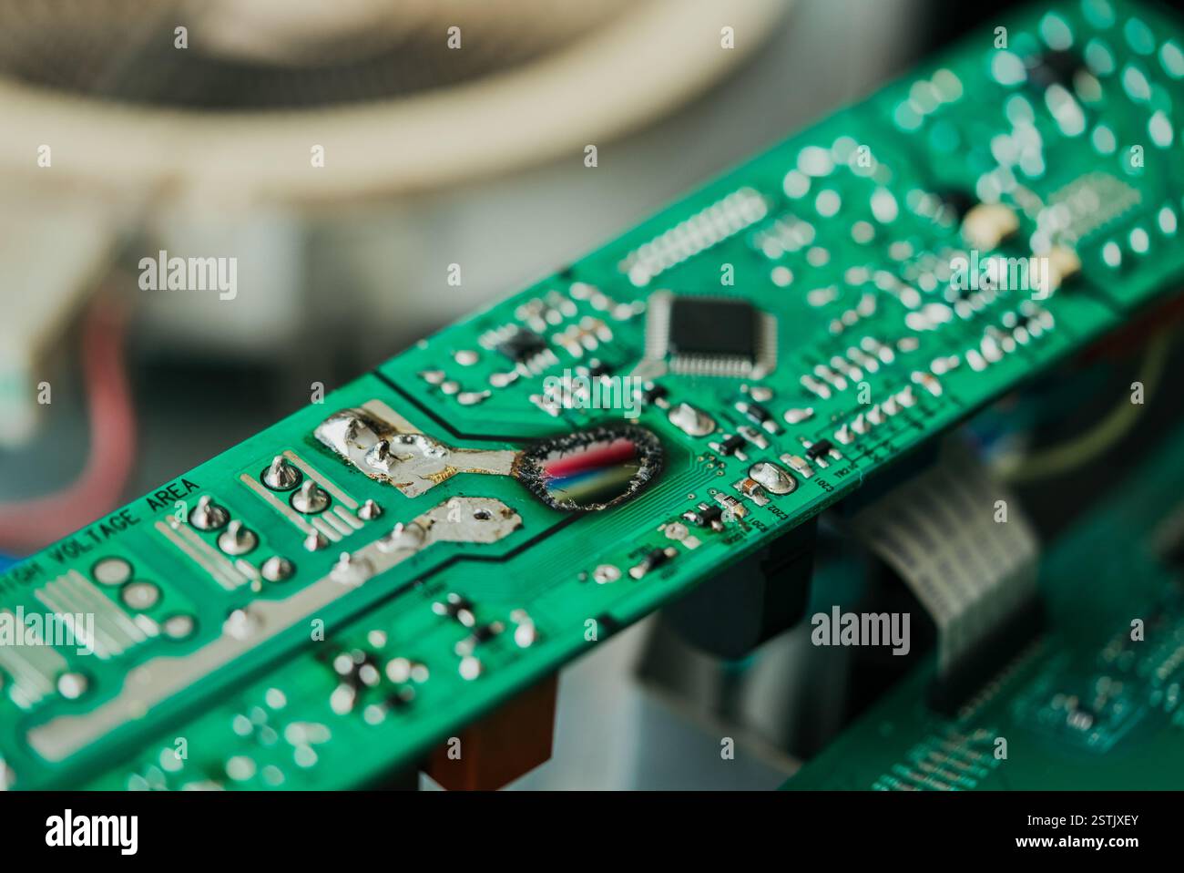 Close-up of a damaged green circuit board with visible burn marks ...