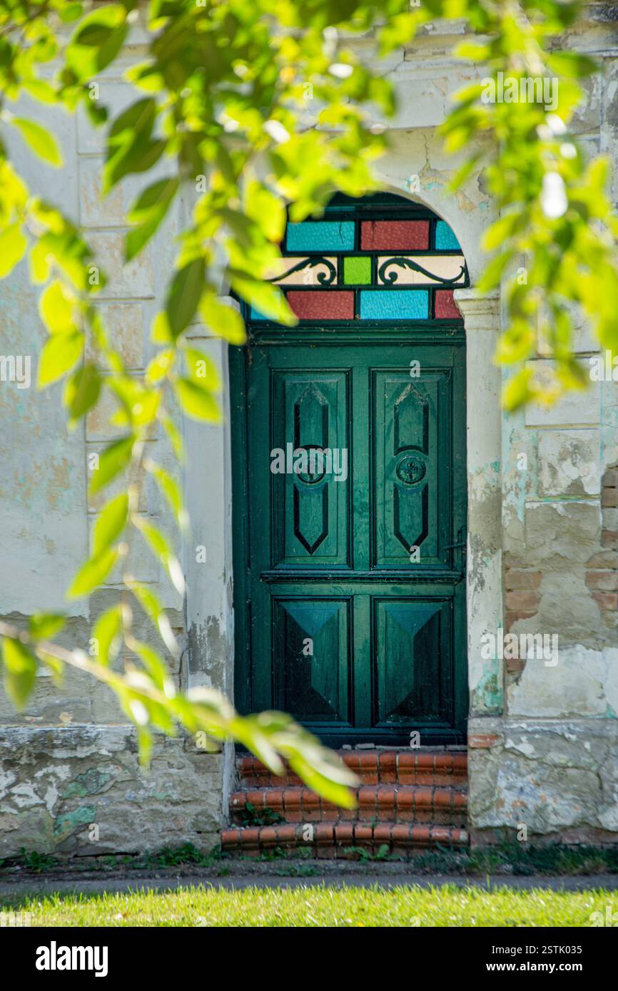 Old dark green wooden door with stained glass window through the tree ...