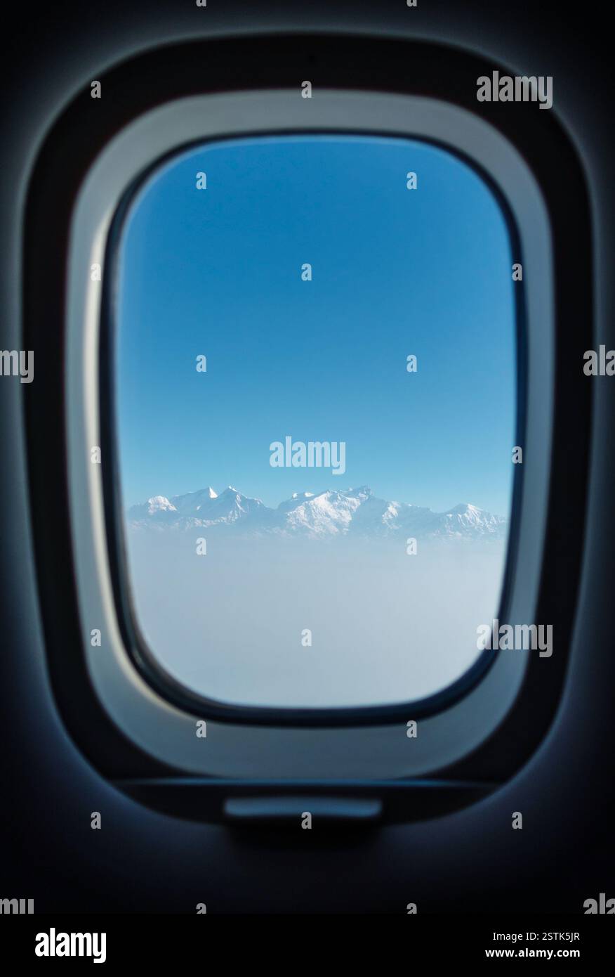Airplane passenger window with a view on the Himalayas during a flight ...