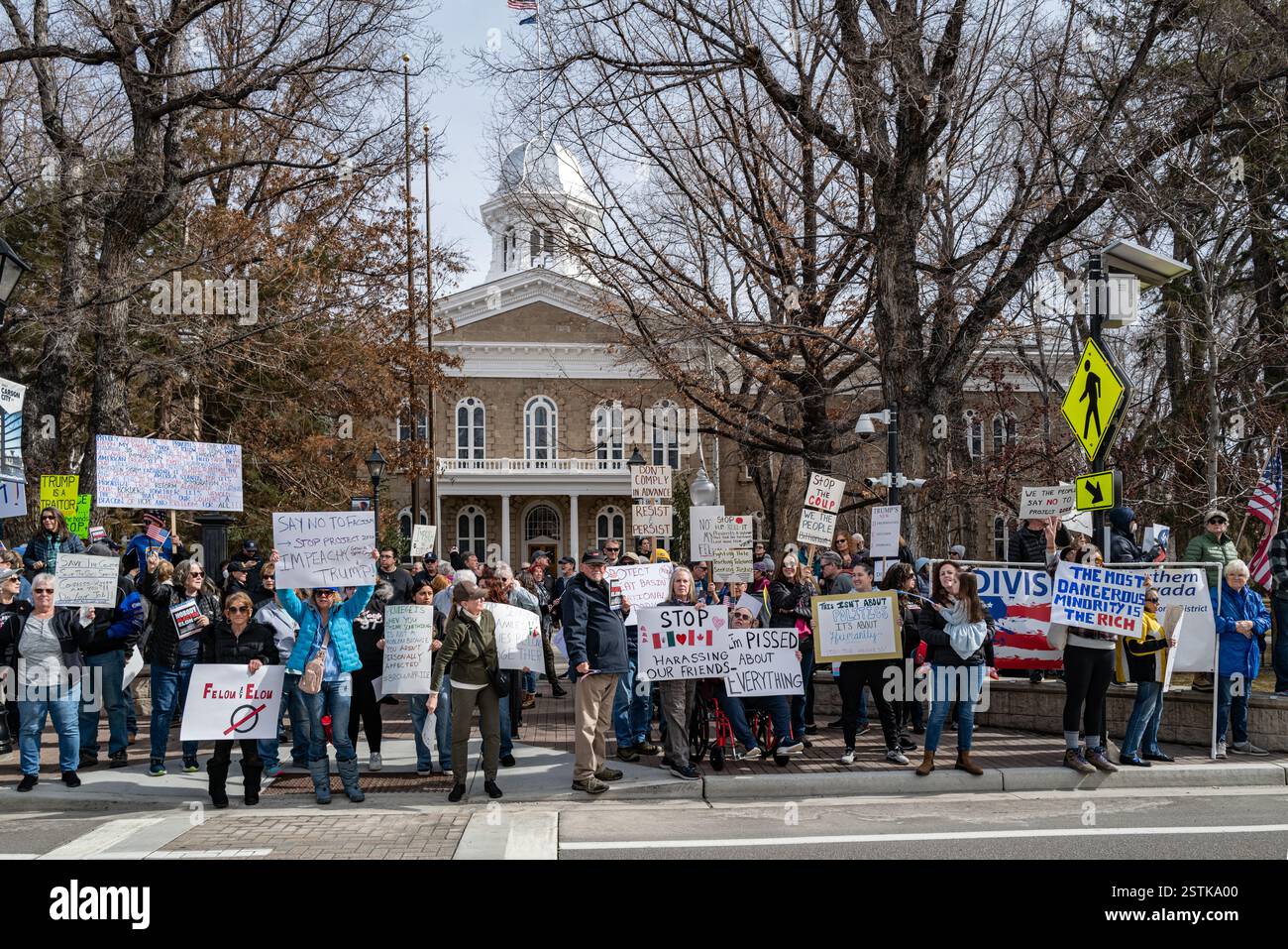 A crowd of protesters engages with motorists driving by on the street ...