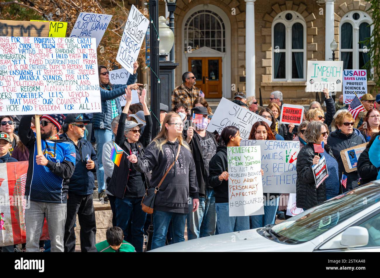 A person waves a Progress Pride flag at motorists on the street with ...