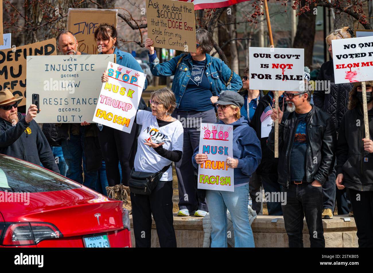 Protesters with anti-Elon Musk sign interact with a Tesla car owner ...
