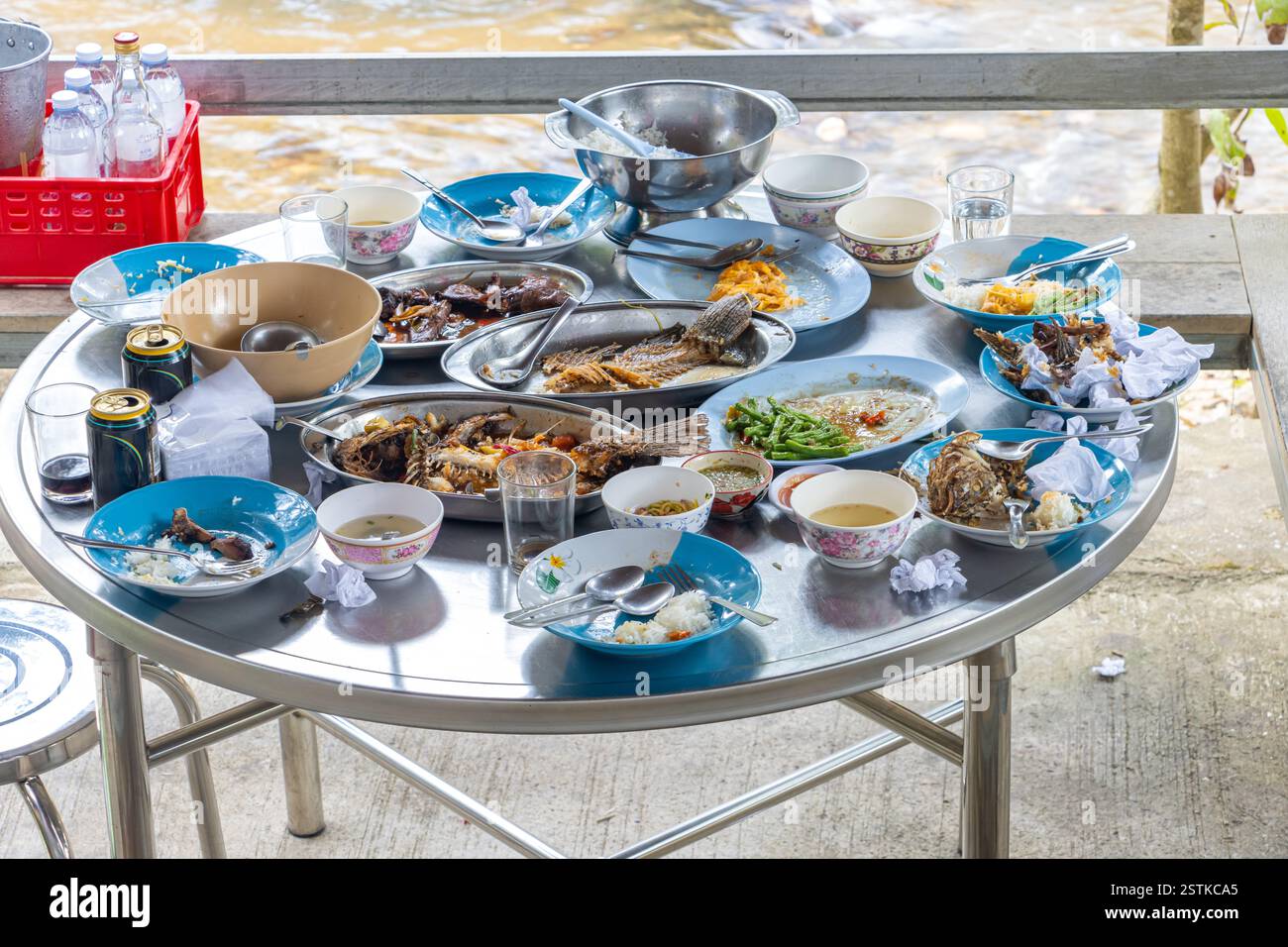 Dirty dishes with leftover food on an oval aluminum table on the porch ...