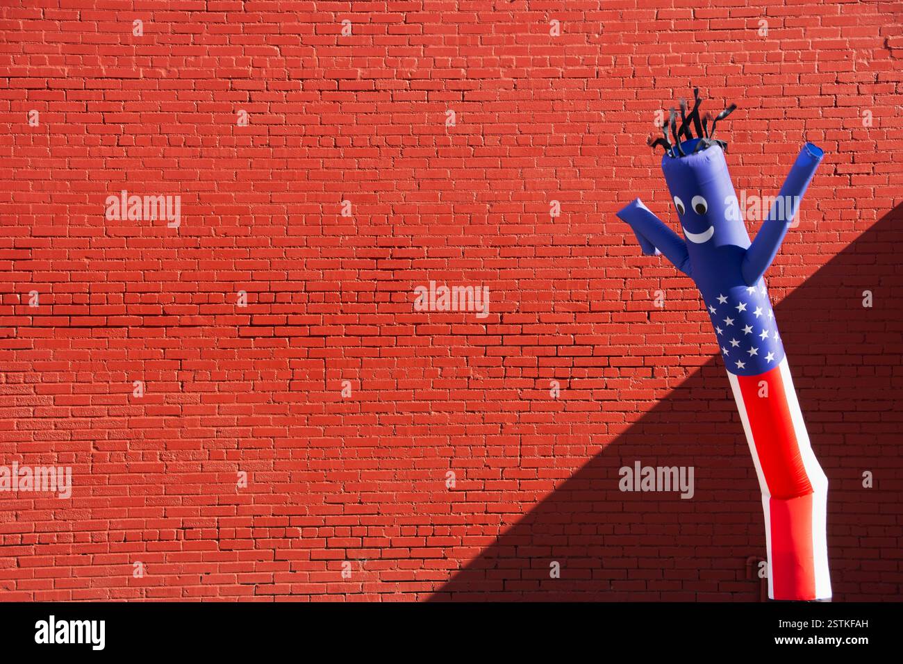 Inflatable tube man with American flag patter against brick wall Stock ...