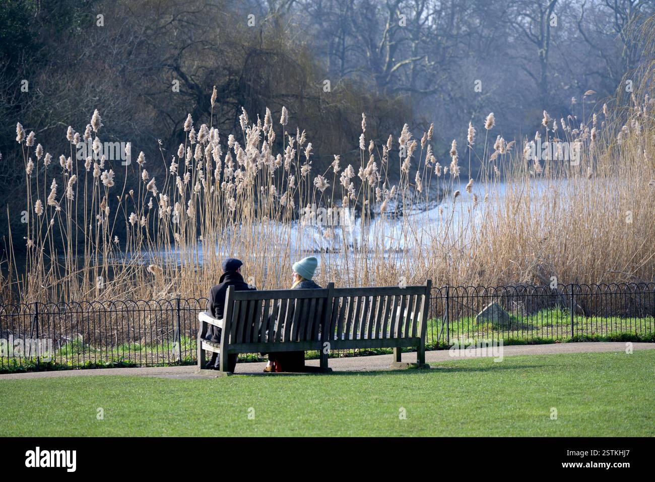 London, UK. Two people sitting on a bench in St James's Park, February ...