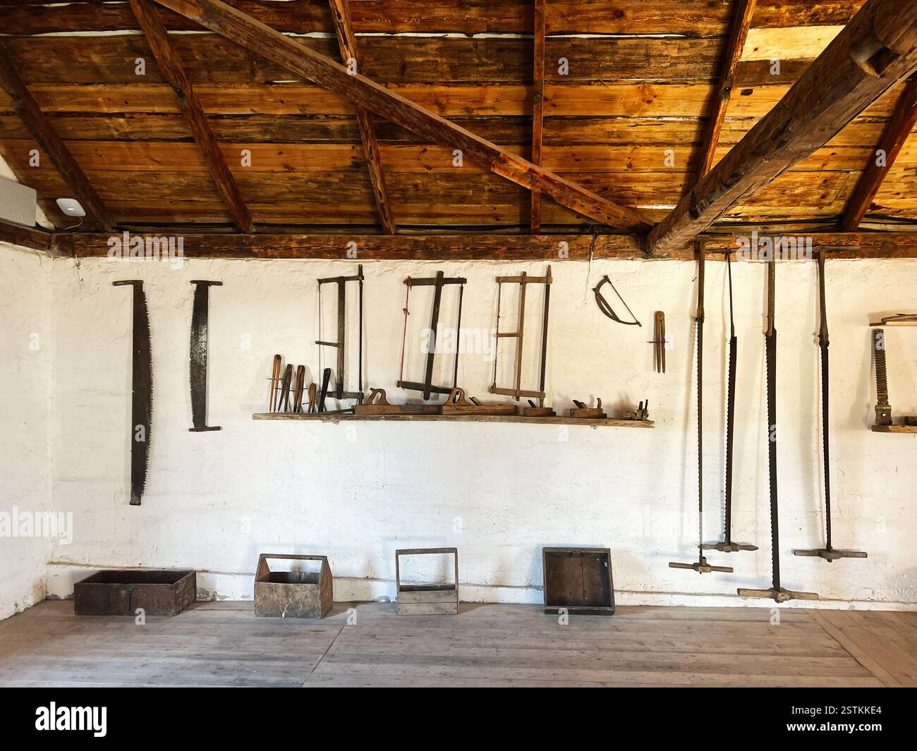 Historic workshop with old carpenter tools hanging on a wood beam wall ...