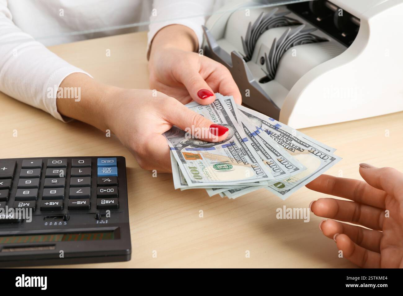 Cashier giving dollar banknotes to client at table in money exchange ...