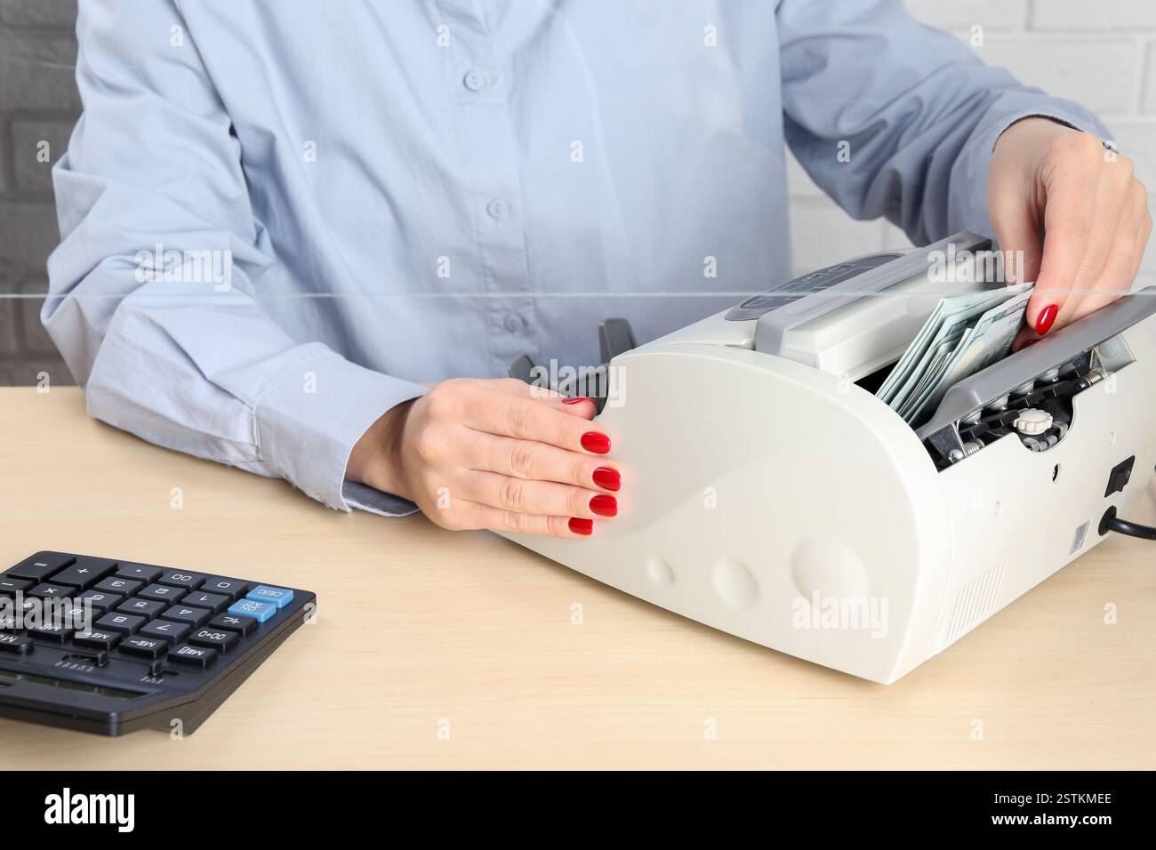 Cashier using money counting machine at table in currency exchange ...