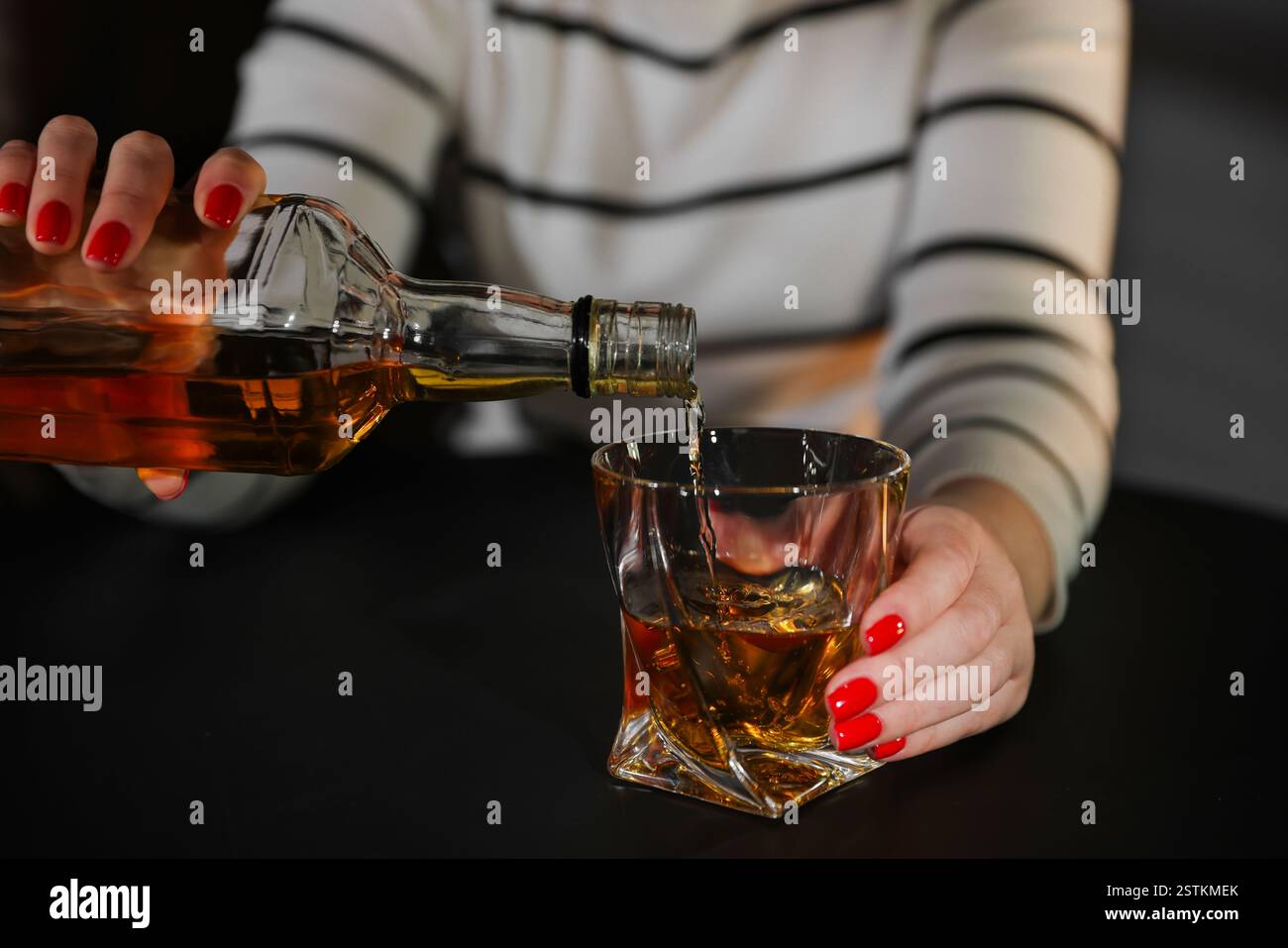Alcohol addiction. Woman pouring whiskey from bottle into glass indoors ...