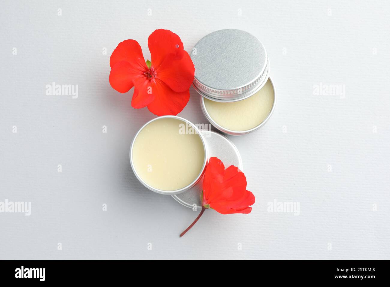 Lip balms and red flowers on white background, top view Stock Photo - Alamy
