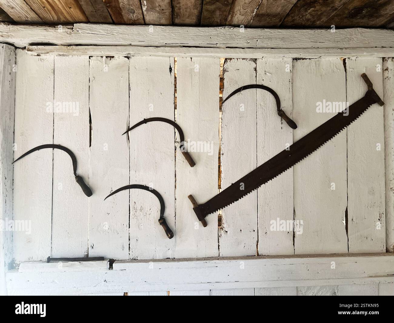 A collection of old-style farming implements fixed on a rustic wooden ...