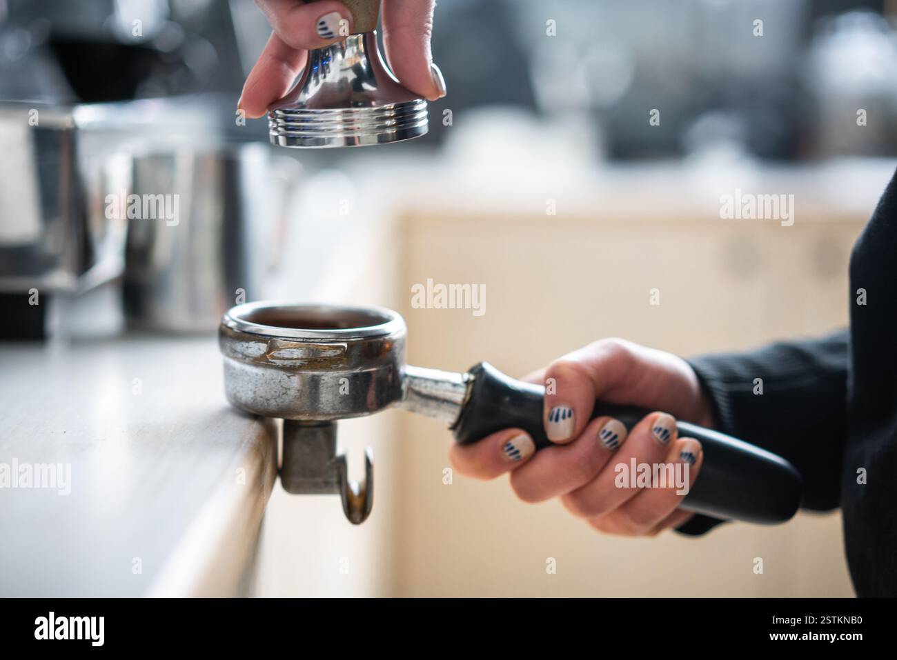 Barista presses ground coffee using tamper Stock Photo - Alamy