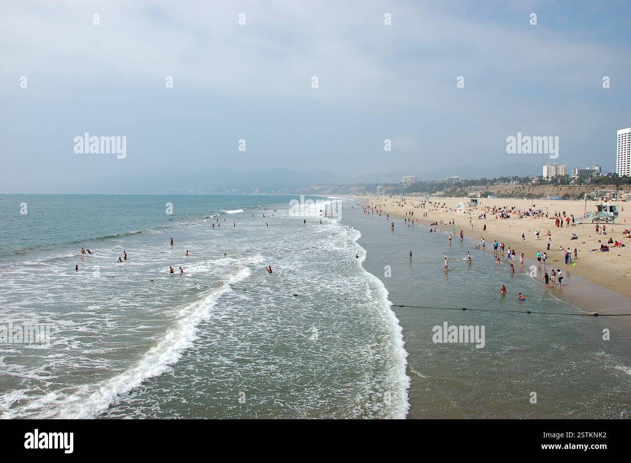 Sunny day at Santa Monica beach with people walking on the sandy shore ...