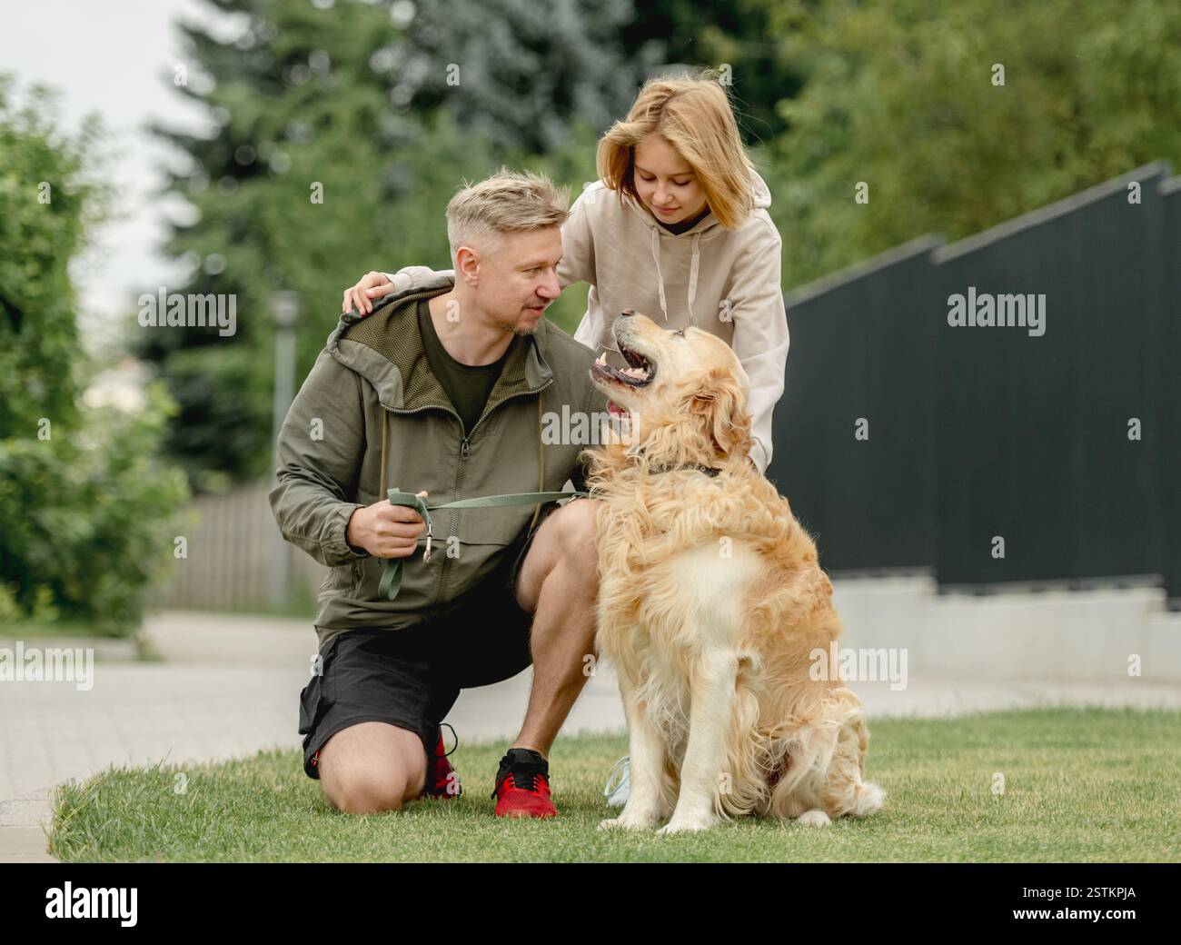 Dad And Daughter Play With Their Golden Retriever Dog During A Walk Stock Photo - Alamy