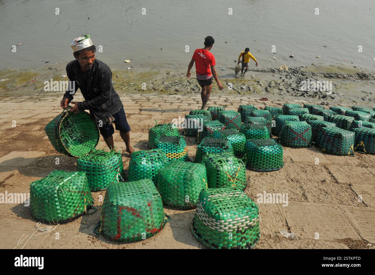 Locals wash fish baskets and dry them on the polluted banks of the ...