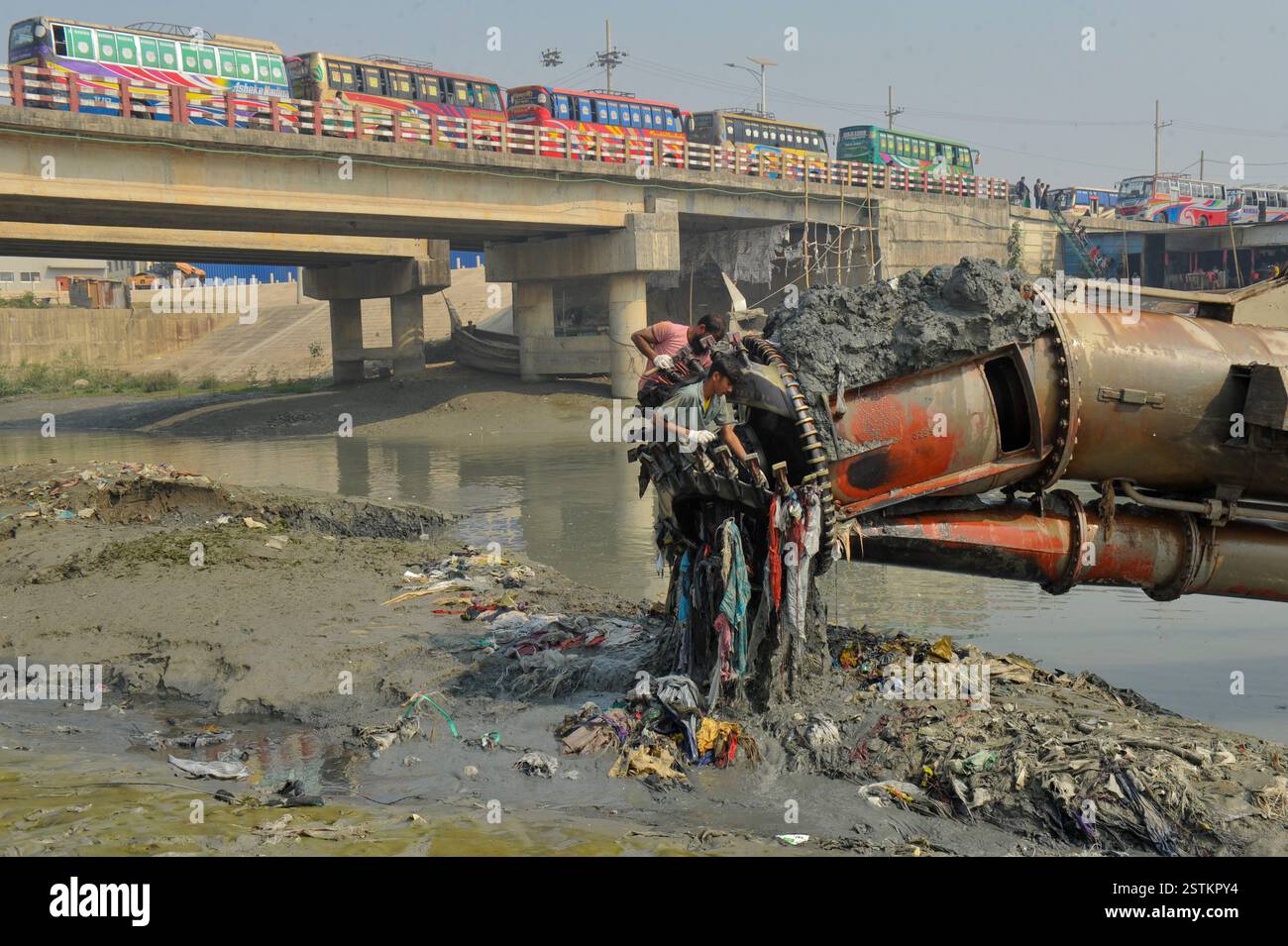 Workers clear plastic and other debris from the grinding head of a ...