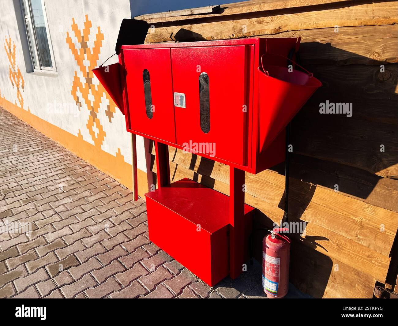 Red firefighting tools and cabinets placed outdoors against a ...