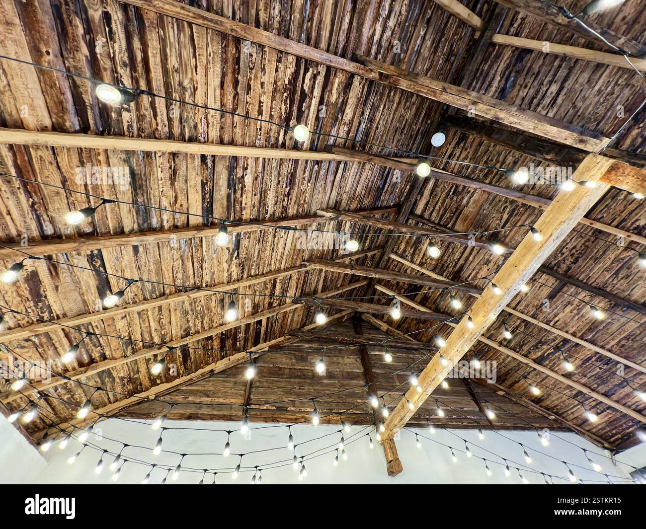 Rustic wooden beams lit by delicate string lights, creating a cozy ...