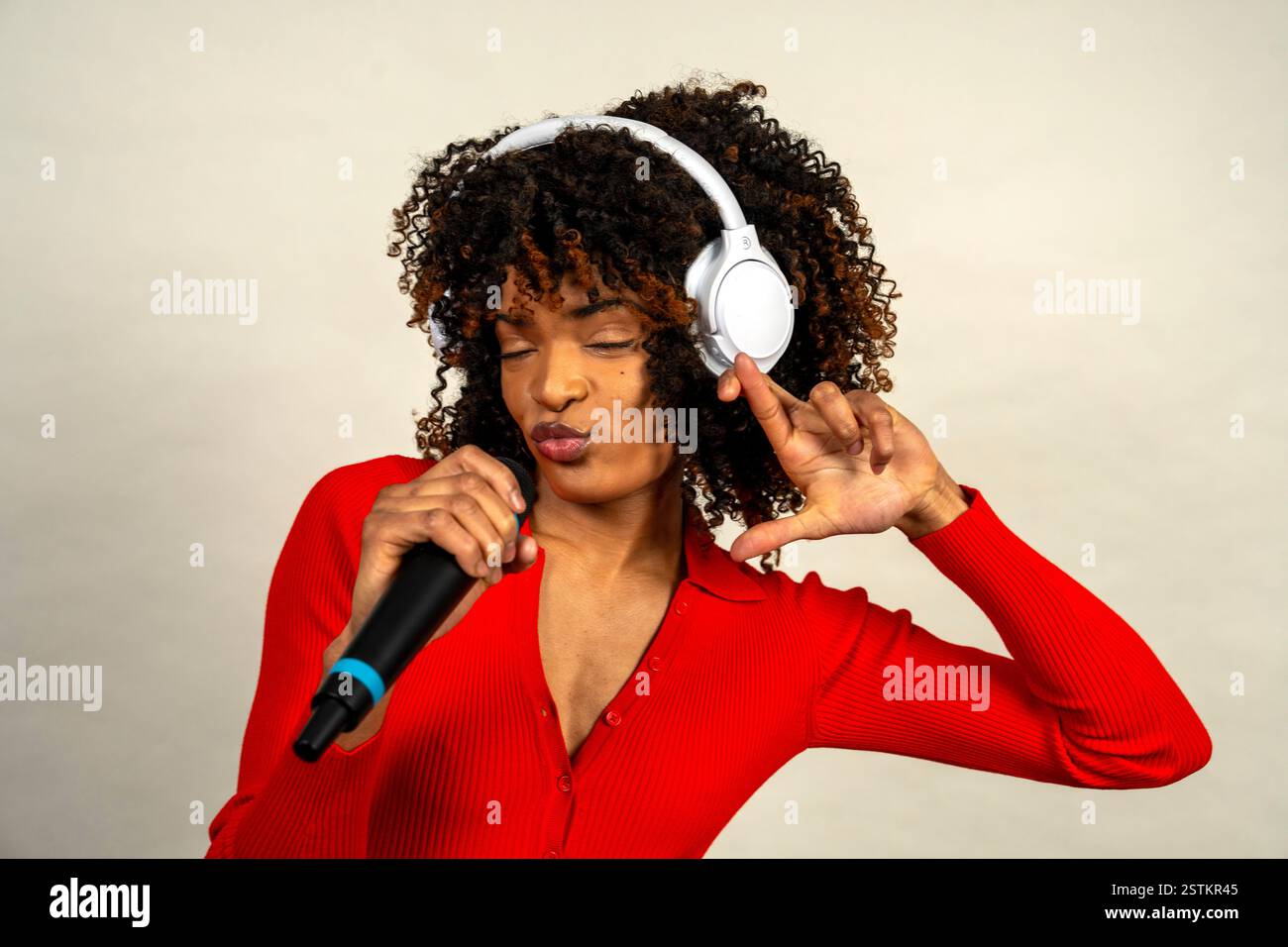 Young woman is singing with headphones and microphone, enjoying music ...