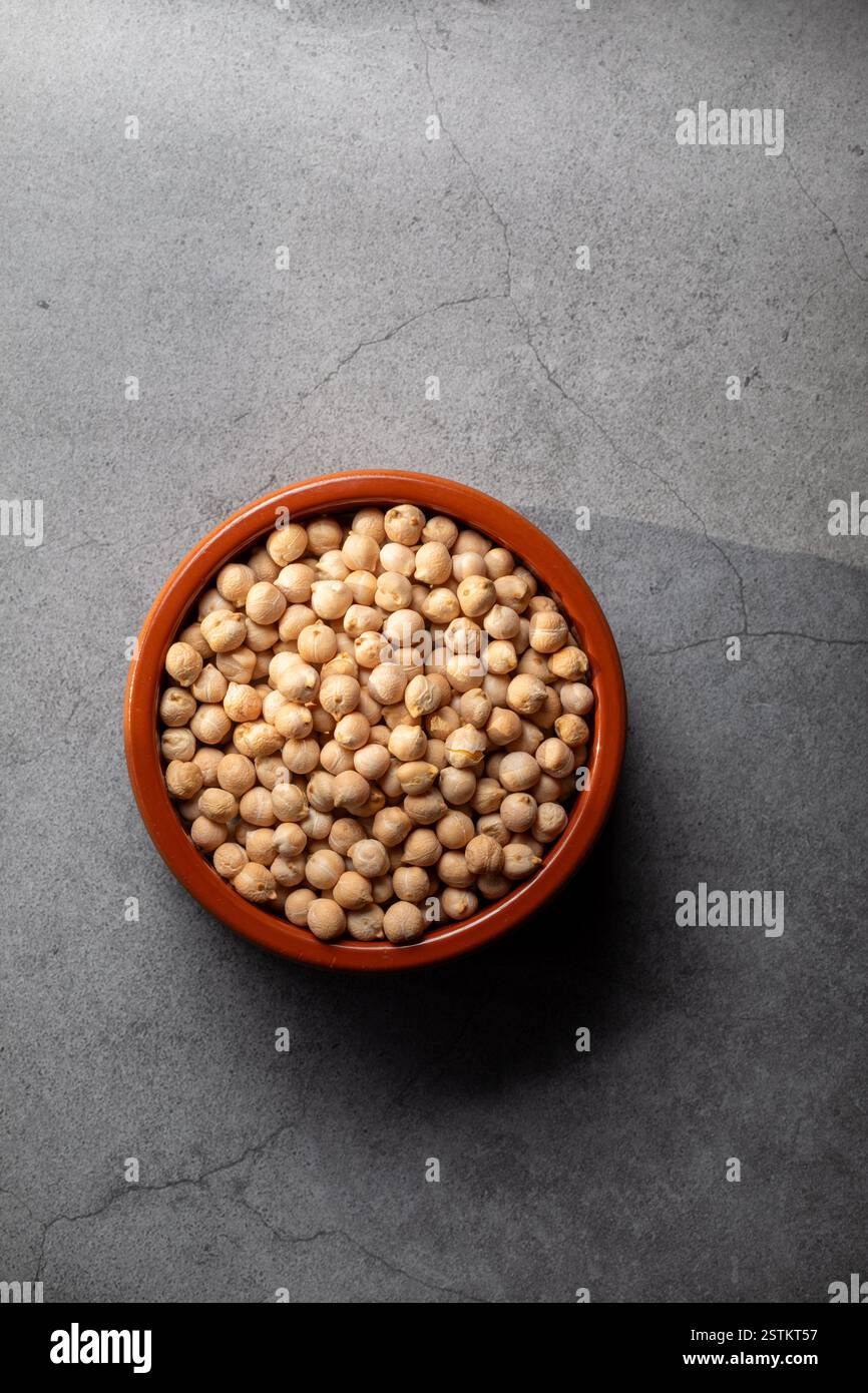 Earthenware bowl full of chickpeas on a kitchen worktop in a zenithal ...