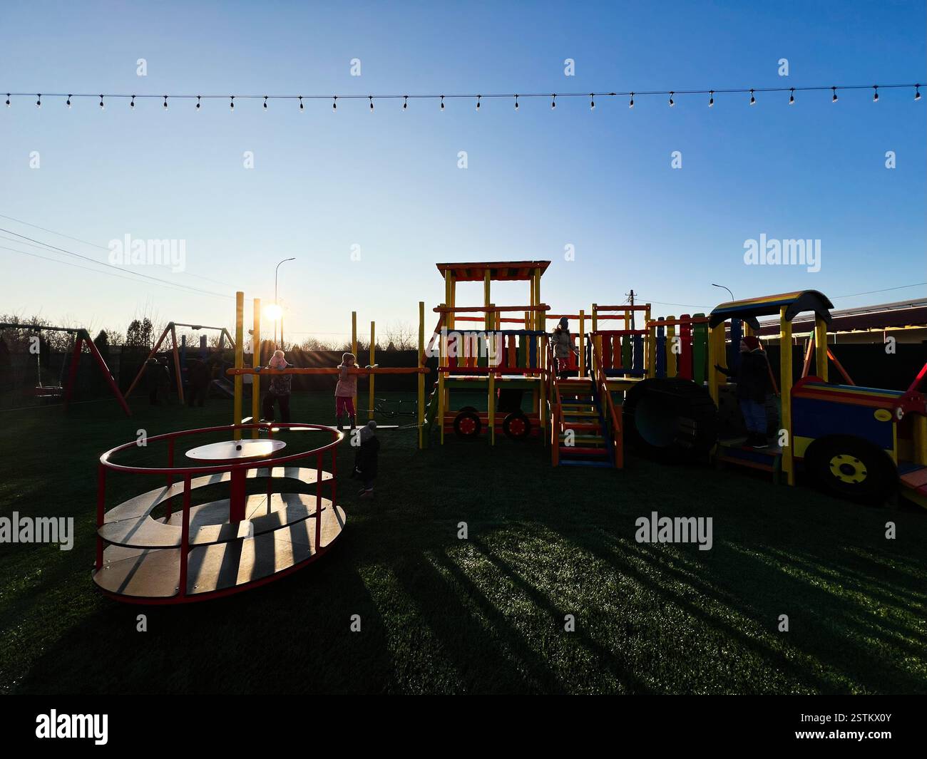 A vibrant playground with children playing under a clear blue sky at ...